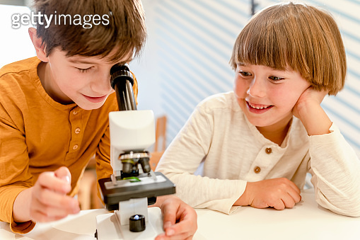 Young children looking through the microscope doing science project in ...