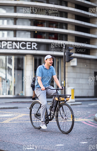 Young man cycling into City of London for work. Healthy life style ...
