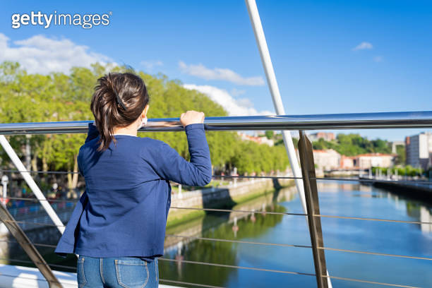 Little girl holding to bridge railing looking at Bilbao river 이미지 ...