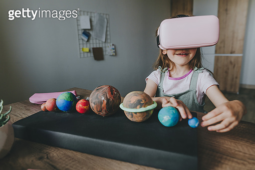 Little girl using VR glasses at home for learning Solar system planets ...