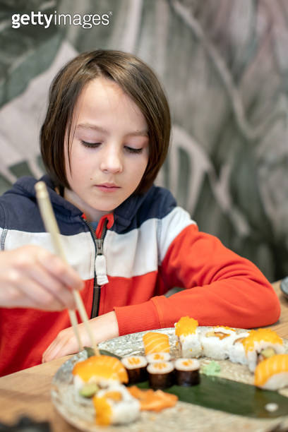 Child, eating japanese sushi and noodles with chopsticks in a ...