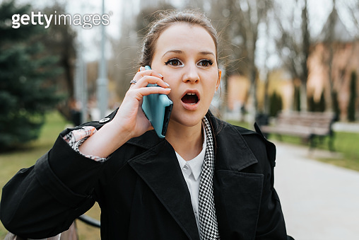 Portrait worried young woman with surprised expression talking on ...