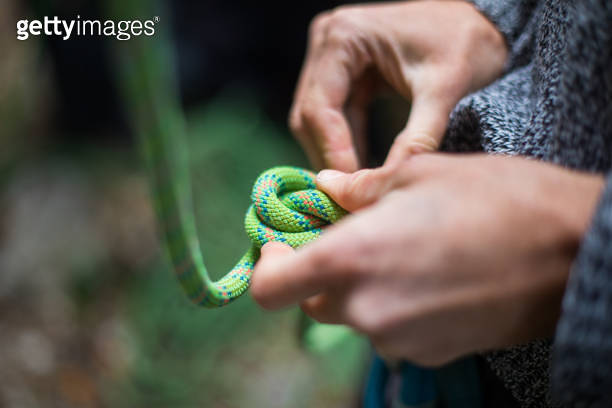 Climber's hands tying a figure eight know to the harness (1358635466 ...