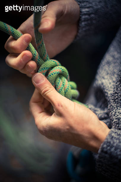 Climber's hands tying a figure eight know to the harness (1358635467 ...