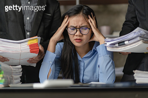 Asian female accountant stressed overtime with loose paperwork and ...