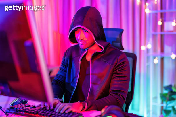 Somewhere in the room hacker wearing hood jacket typing computer ...
