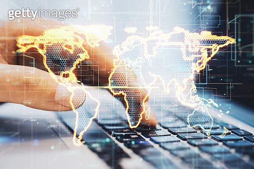 Close up of businessman hands using laptop keyboard with abstract glowing golden map hologram on ...