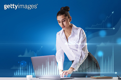 Attractive young caucasian businesswoman leaning on desktop with laptop ...