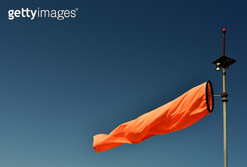 Bright neon orange wind sock blowing indicating wind direction against ...