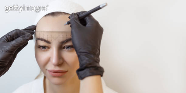 Eyebrow tattooing .Permanent eyebrow makeup master applies the contour ...