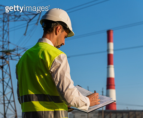 Electric power industry, engineer in field checking power line project ...