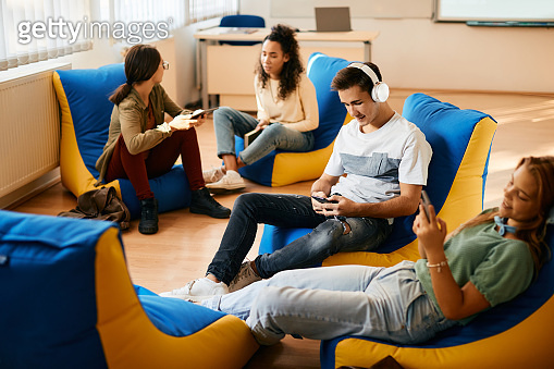 Group of teenagers relaxing on bean bangs during a break in the ...