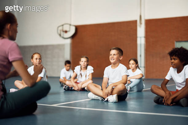 Happy elementary student and his classmates having PE class with female ...