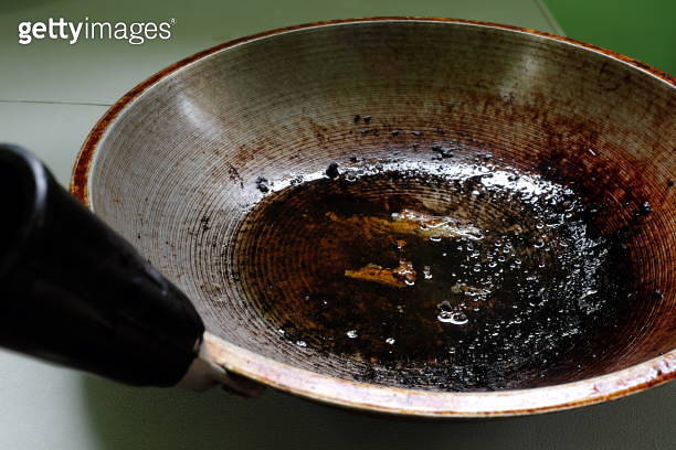 Closeup of burnt, scorched and greasy pan or wok with cooking oil in ...