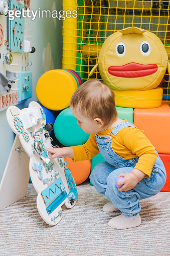 A little girl is playing with busy board in the playroom 이미지 ...