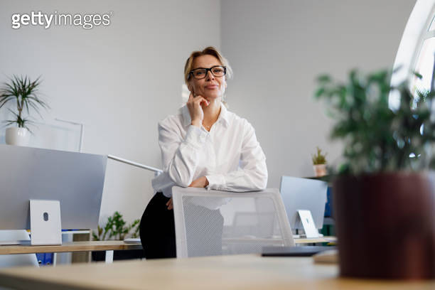 Joyful mature business woman leaning against the back of the chair in ...