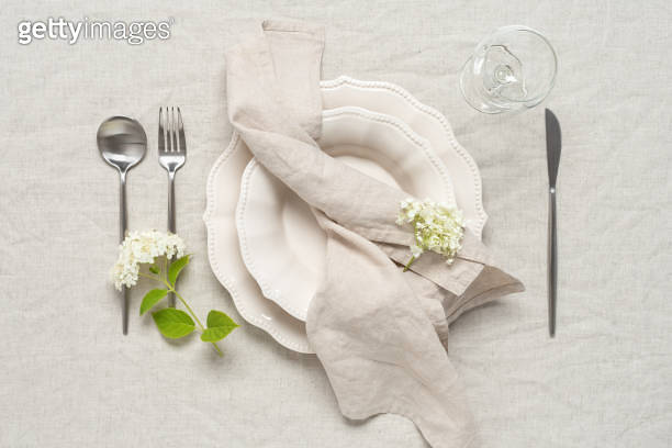 Wedding table setting. Beige plates, a beige linen napkin and white ...