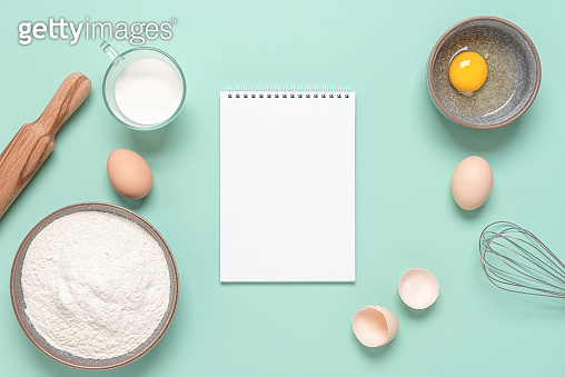 Baking ingredients and a blank notepad. Mint pastel color background ...