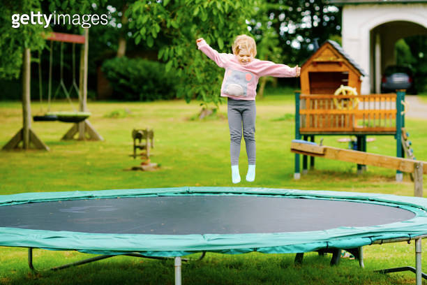Little preschool girl jumping on trampoline. Happy funny toddler child ...