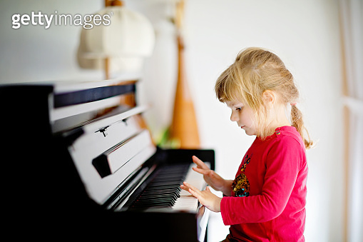 Beautiful little toddler girl playing piano in living room. Cute ...
