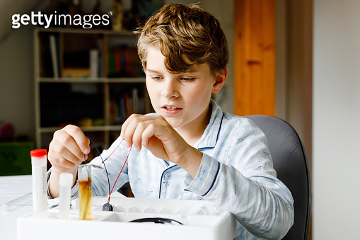 Preteen kid boy doing electric physical experiment as homework at home ...