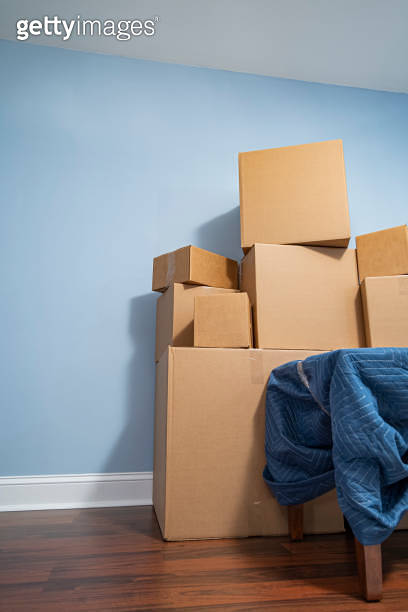A stack of carboard moving boxes and a small table covered in a moving ...