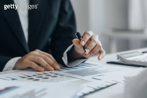 A business finance woman is reviewing a company's financial documents prepared by the Finance ...
