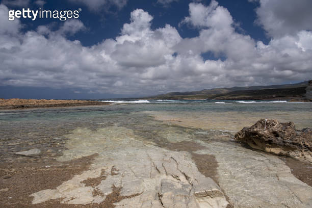 Limestone shelf in calm rugged coastal region's lagoon with breaking ...
