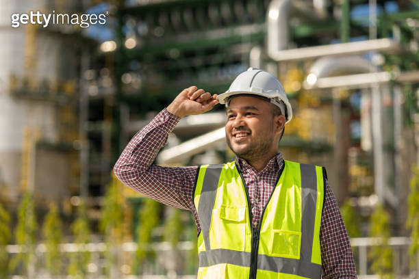 Asian engineer man with white safety helmet standing front of oil ...
