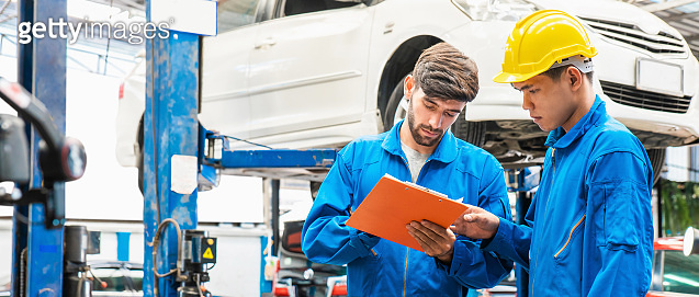 Mechanic in blue work wear uniform checks the vehicle maintenance ...