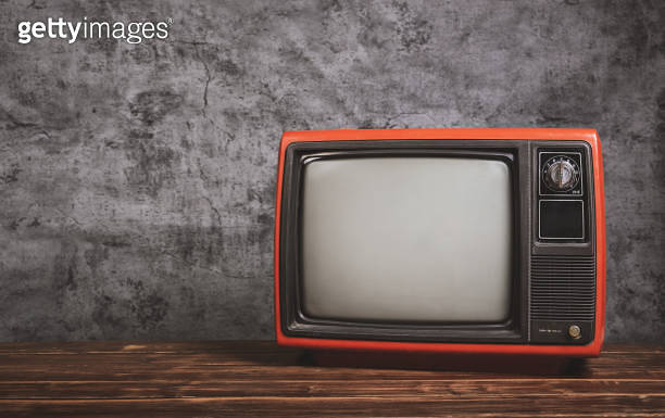 Retro old television on wooden table in front of concrete wall ...