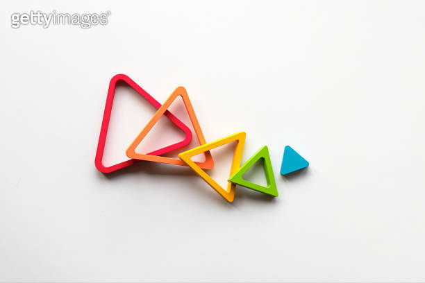 Nested wooden triangles painted in rainbow colors. Flat lay on white ...