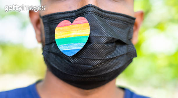 close up shot of man with pride or rainbow heart symbol on medical face ...