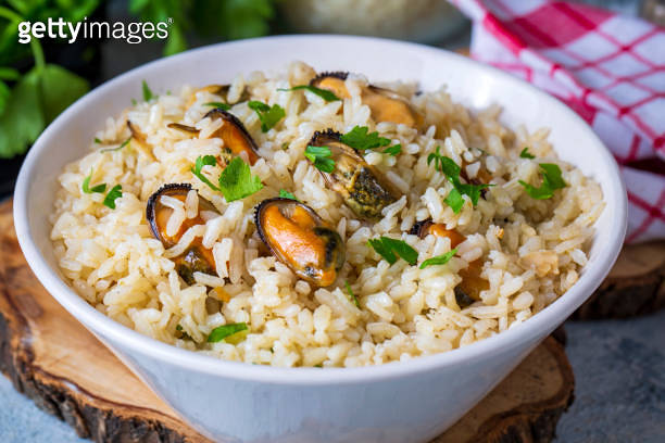 Mussel rice pilaf. Rice with mussels on small white plate on ceramic ...