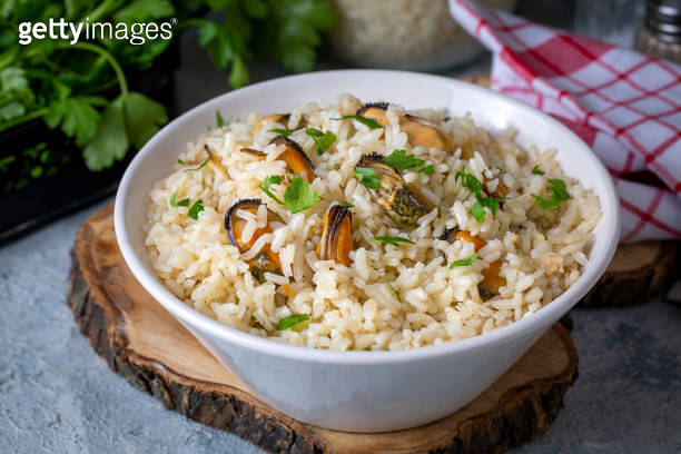 Mussel rice pilaf. Rice with mussels on small white plate on ceramic ...