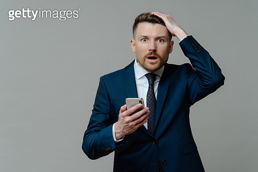 Shocked businessman in suit feeling upset while receiving unexpected ...