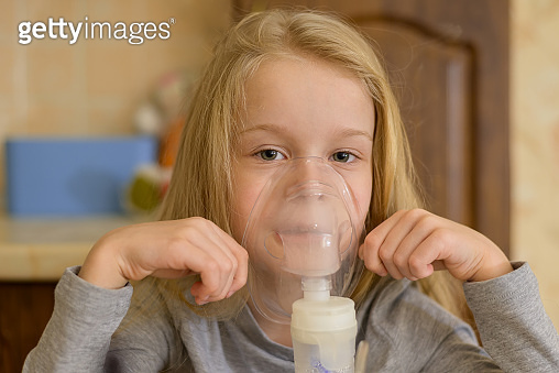 a sick child makes inhalation with a nebulizer at home: he holds a mask ...