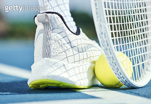 Cropped shot of an unrecognisable man using his foot and racket to pick ...