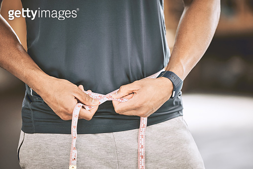 Hands of a bodybuilder measuring his waist. Fit trainer using tape ...