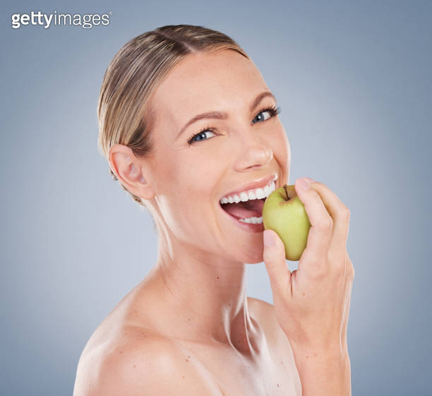 Studio portrait of an attractive young woman posing with an apple ...