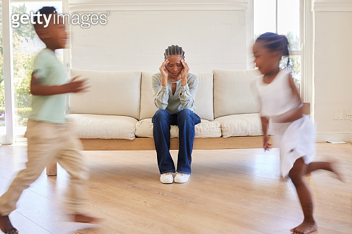 Shot of a young mother looking exhausted while her children run around ...