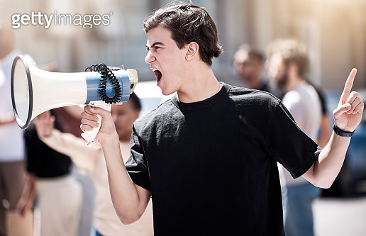 Shot of a young man yelling through a megaphone during a protest 이미지 ...