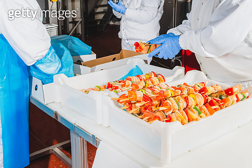 Chicken Skewers,ready to cook.Group of workers pack chicken skewers ...
