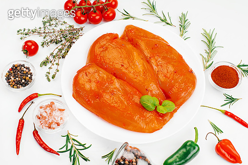 Raw marinated chicken fillet in red sauce on white plate on white ...