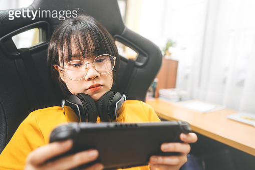 Nerd style young adult asian gamer woman wear eyeglasses and headphone ...