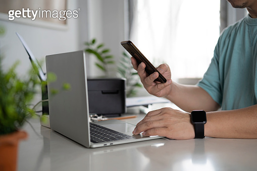 Business man using mobile smart phone, busy working on laptop computer 이미지 (1362322943) - 게티이미지뱅크