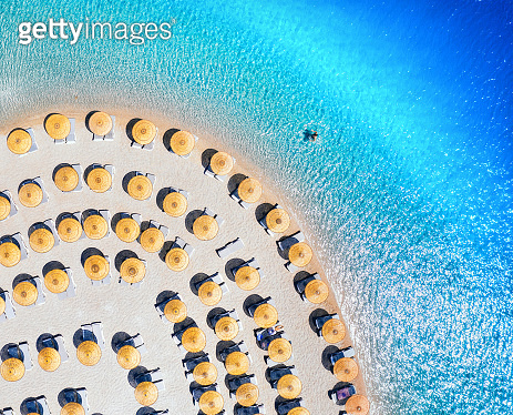 Aerial view of blue sea, empty sandy beach with sun beds and umbrellas ...
