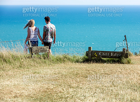 Two unknown people ignore danger signs on a cliff (1397918076) - 게티이미지뱅크