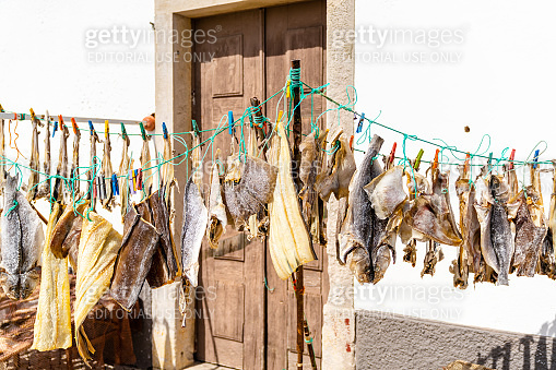 many strips of salted codfish or bacalao drying in front of a small ...