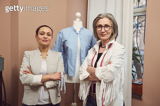 Skilled inspired confident team of two women tailors posing with a ...